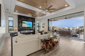 Uma sala de estar espaçosa com uma televisão grande, teto de madeira e uma varanda com vista.