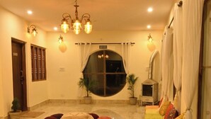 Um hall amplo com uma grande janela redonda, assentos confortáveis e um lustre.