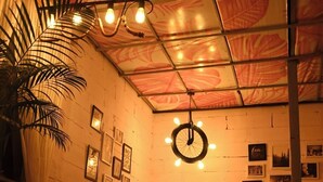 Um quarto com um cavalete de madeira, luminária na parede e quadros emoldurados.