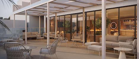 Uma área de estar moderna ao ar livre, com assentos, um bar envidraçado e vista para o interior.