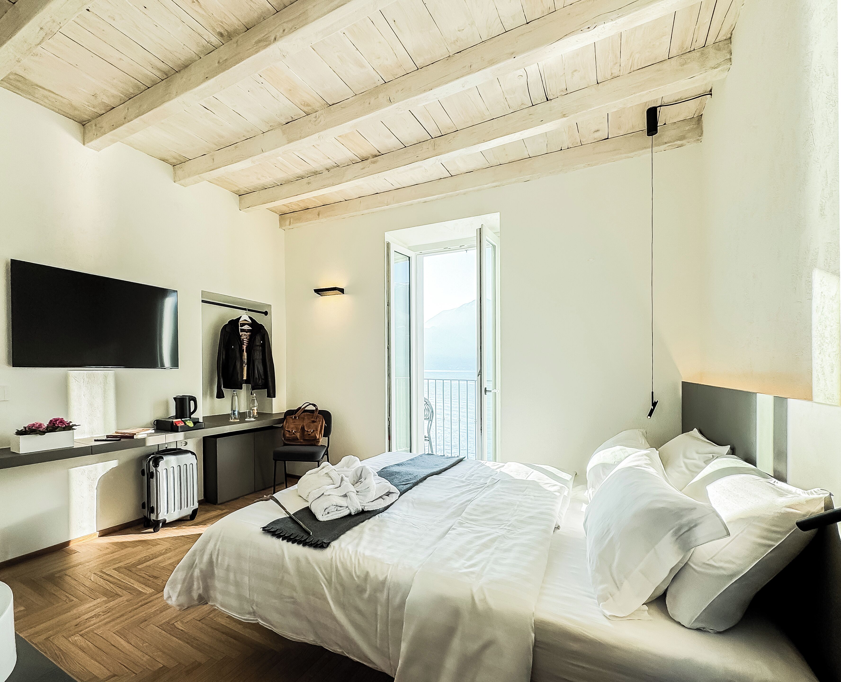 Quarto de hotel com cama, escrivaninha, computador, televisão e janela com vista.