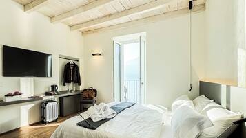 Quarto de hotel com cama, escrivaninha, computador, televisão e janela com vista.