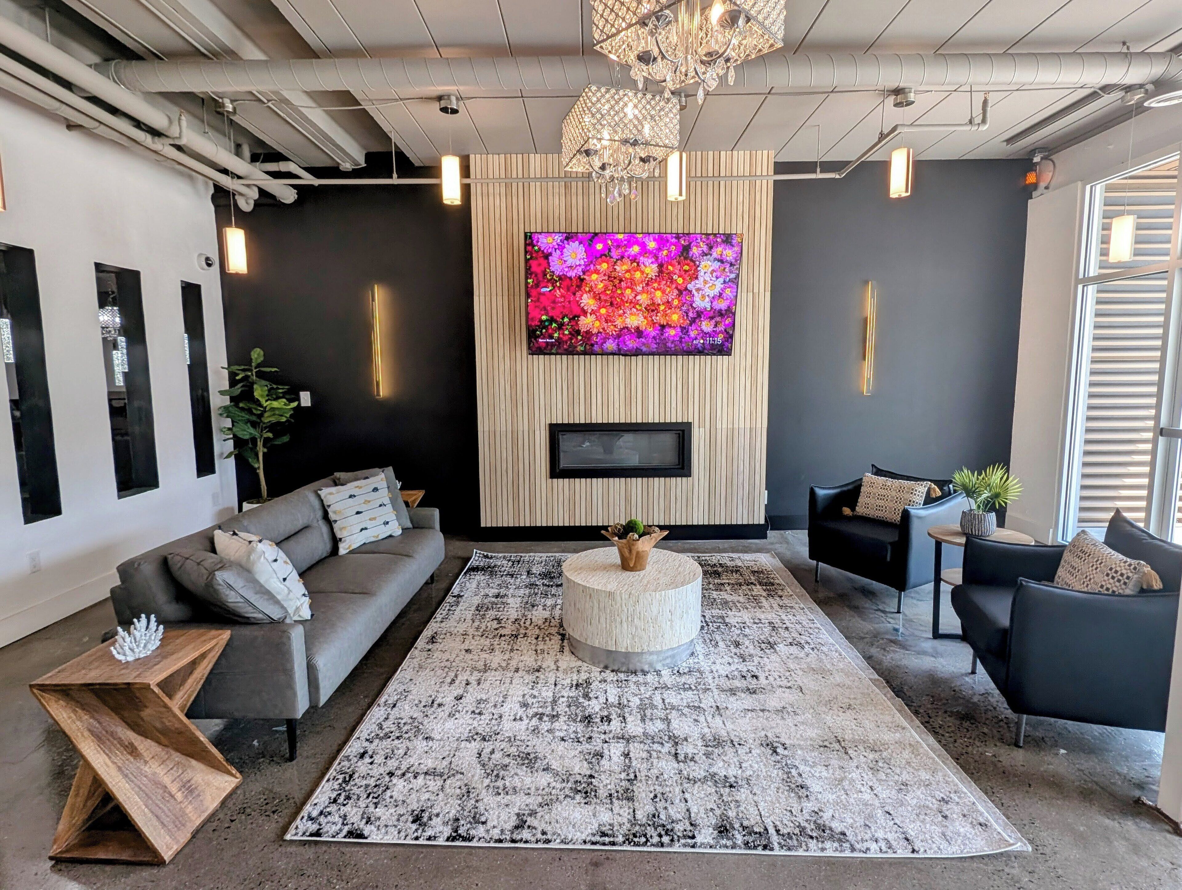 Uma sala de estar moderna com uma televisão de tela plana grande, uma mesa de centro redonda e dois sofás.