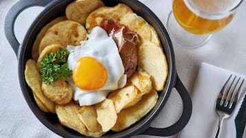 Uma frigideira com um ovo frito, bacon e batatas fritas.