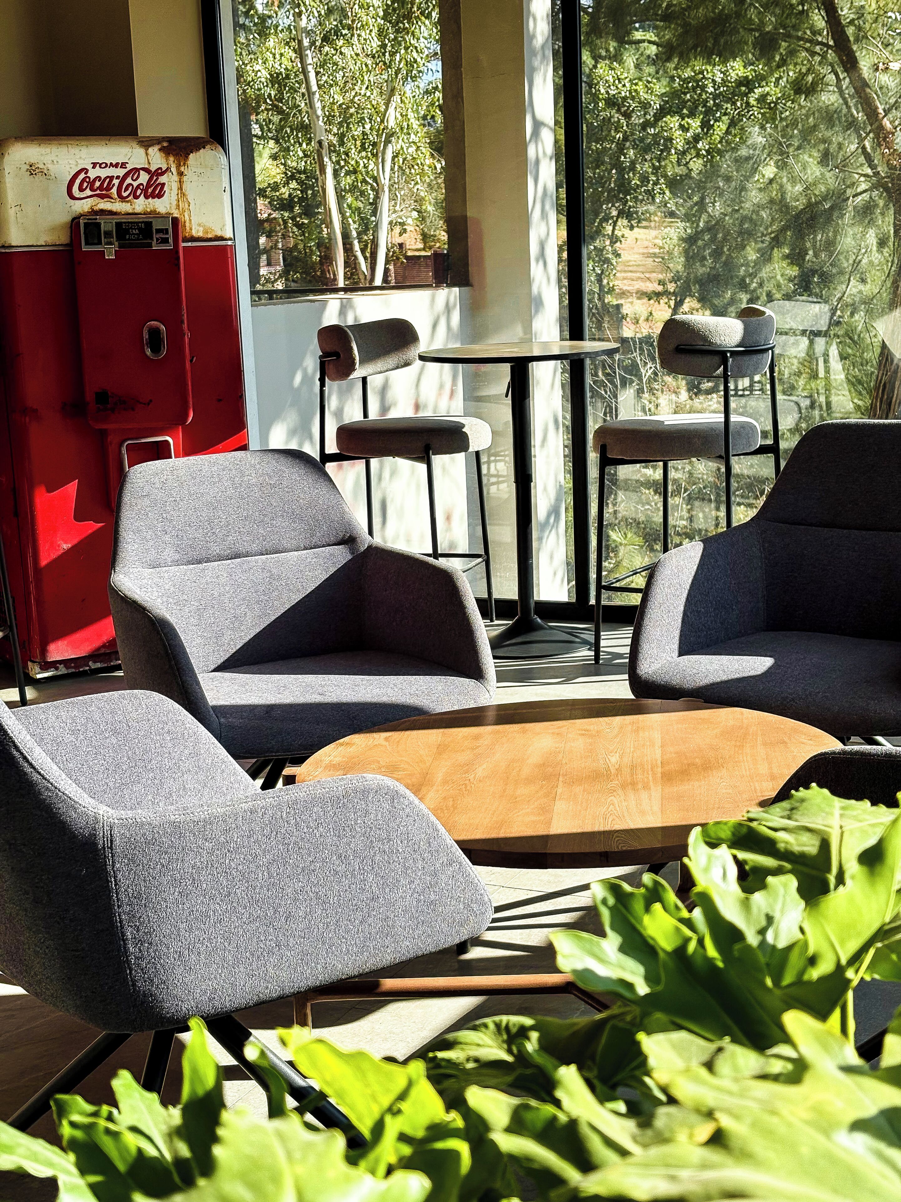 Uma área de estar moderna ao ar livre, com cadeiras cinzas estofadas e uma mesa de centro de madeira.