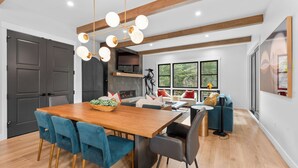 Cozinha moderna com mesa de jantar de madeira, cadeiras azuis e uma luminária pendente.