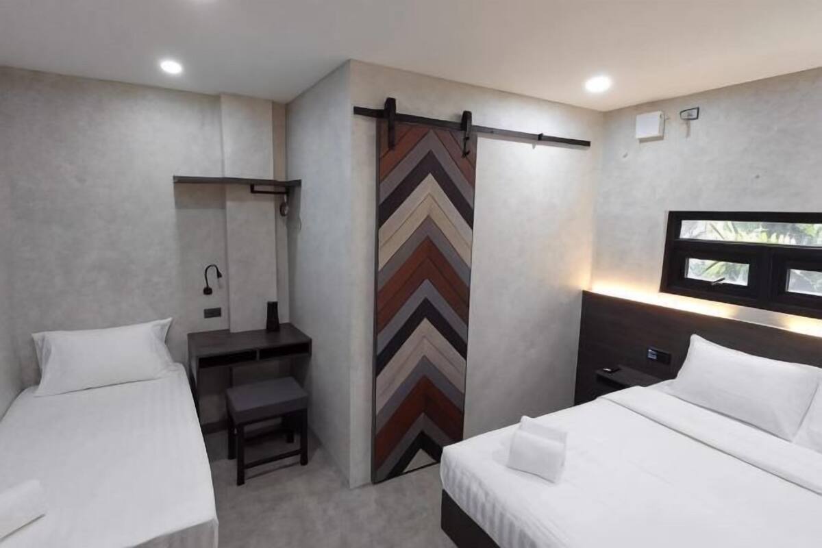 Quarto com duas camas, uma escrivaninha, uma cadeira, um guarda-roupa e um espelho.