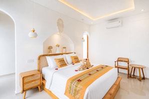 Quarto moderno com cama, mesas de cabeceira, uma cadeira e uma pequena mesa.