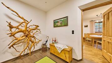 Um quarto com uma escultura de árvore em madeira, um banco com tecido, uma pintura e uma área de jantar com mobiliário de madeira.