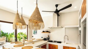 Uma cozinha moderna com uma ilha central, luminárias trançadas penduradas e um ventilador de teto.