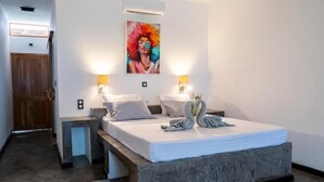 Quarto com cama, luminárias de cabeceira, um quadro e uma porta.