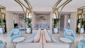 Um hall amplo com área de estar central, paredes espelhadas e plantas em vasos.