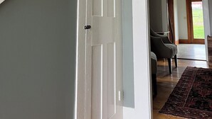 Uma escadaria com corrimãos de madeira leva a um quarto com uma porta branca.
