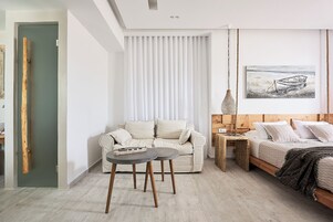 Quarto moderno com cama, sofá, mesa pequena e um quadro na parede.
