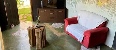 Uma sala de estar moderna com um sofá vermelho, uma mesa de centro de madeira e um quadro abstrato grande na parede.