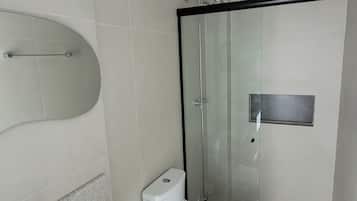 Um banheiro moderno com box de vidro, vaso sanitário branco e bancada de granito com pia.