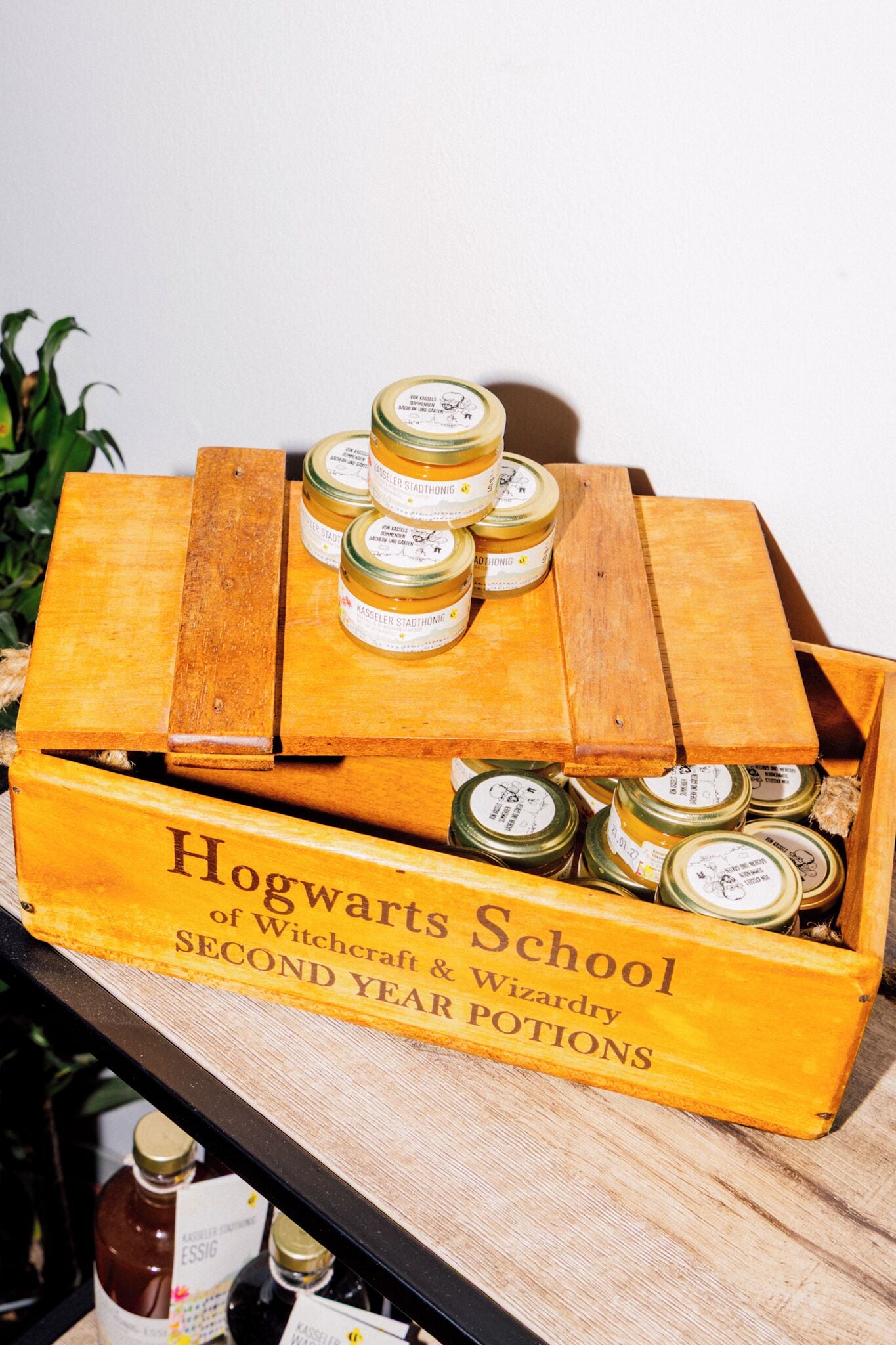 Uma caixa de madeira com a etiqueta 'Hogwarts School of Witchcraft & Wizardry Segundo Ano Poções', com potes de poções.