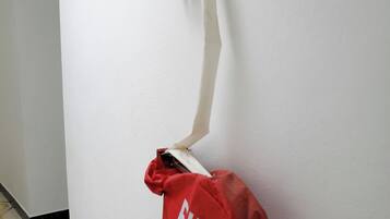 Corredor com mangueira de incêndio fixada na parede e uma bolsa vermelha com a inscrição 'FIRE HOSE CLEAR'.