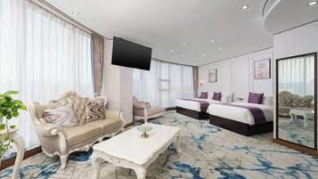 Quarto de hotel com sofá, cama, televisão e uma janela grande.