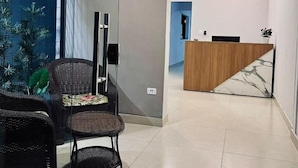 Uma área de recepção moderna, com balcão de madeira, divisória de vidro e mobiliário de vime.