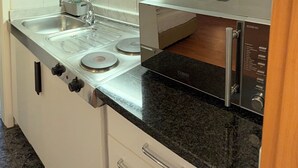 Cozinha compacta com pia, fogão e torradeira.