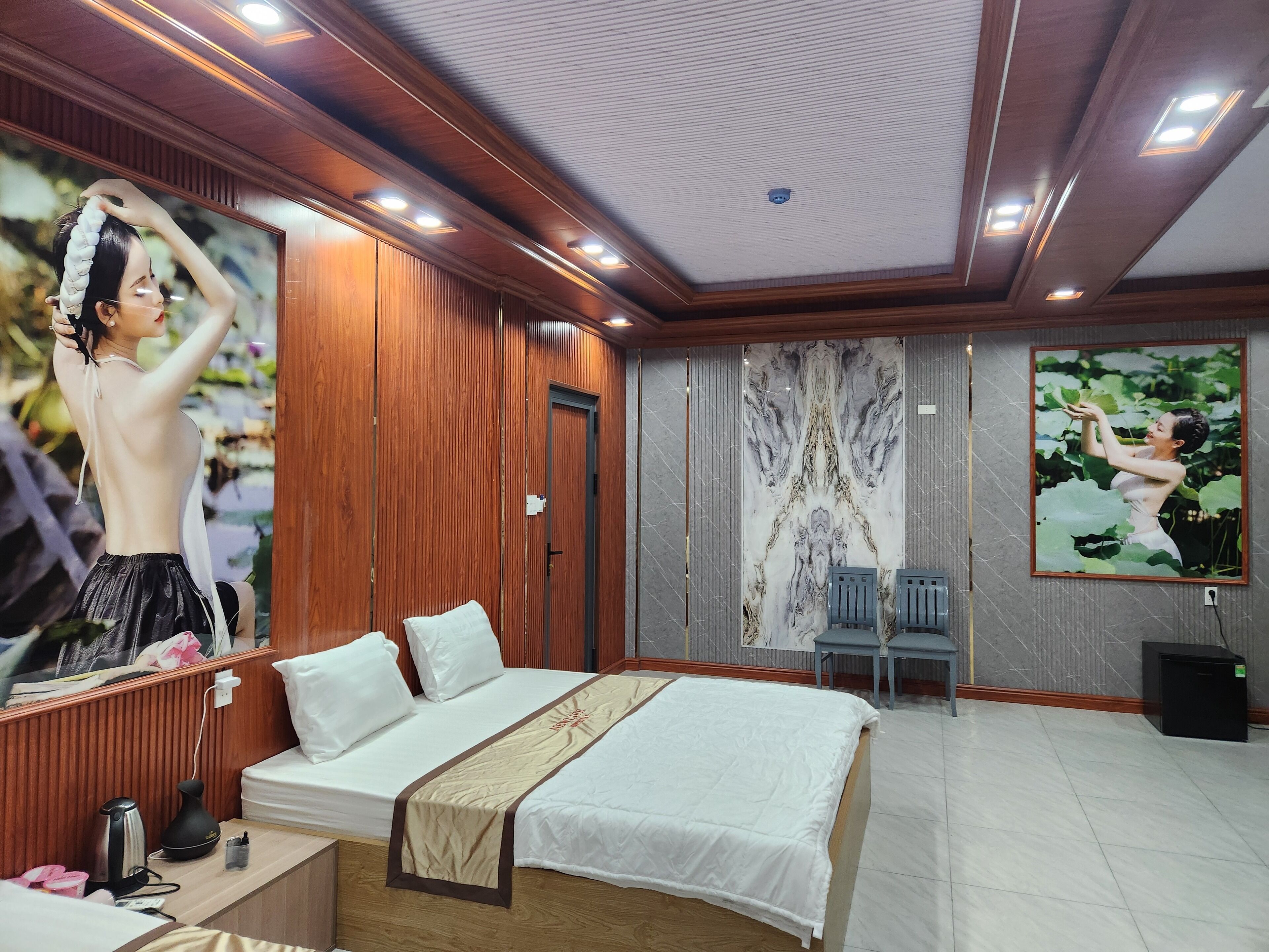 Quarto de hotel com uma cama, uma escrivaninha, uma cadeira, um espelho e uma parede com um quadro grande emoldurado.