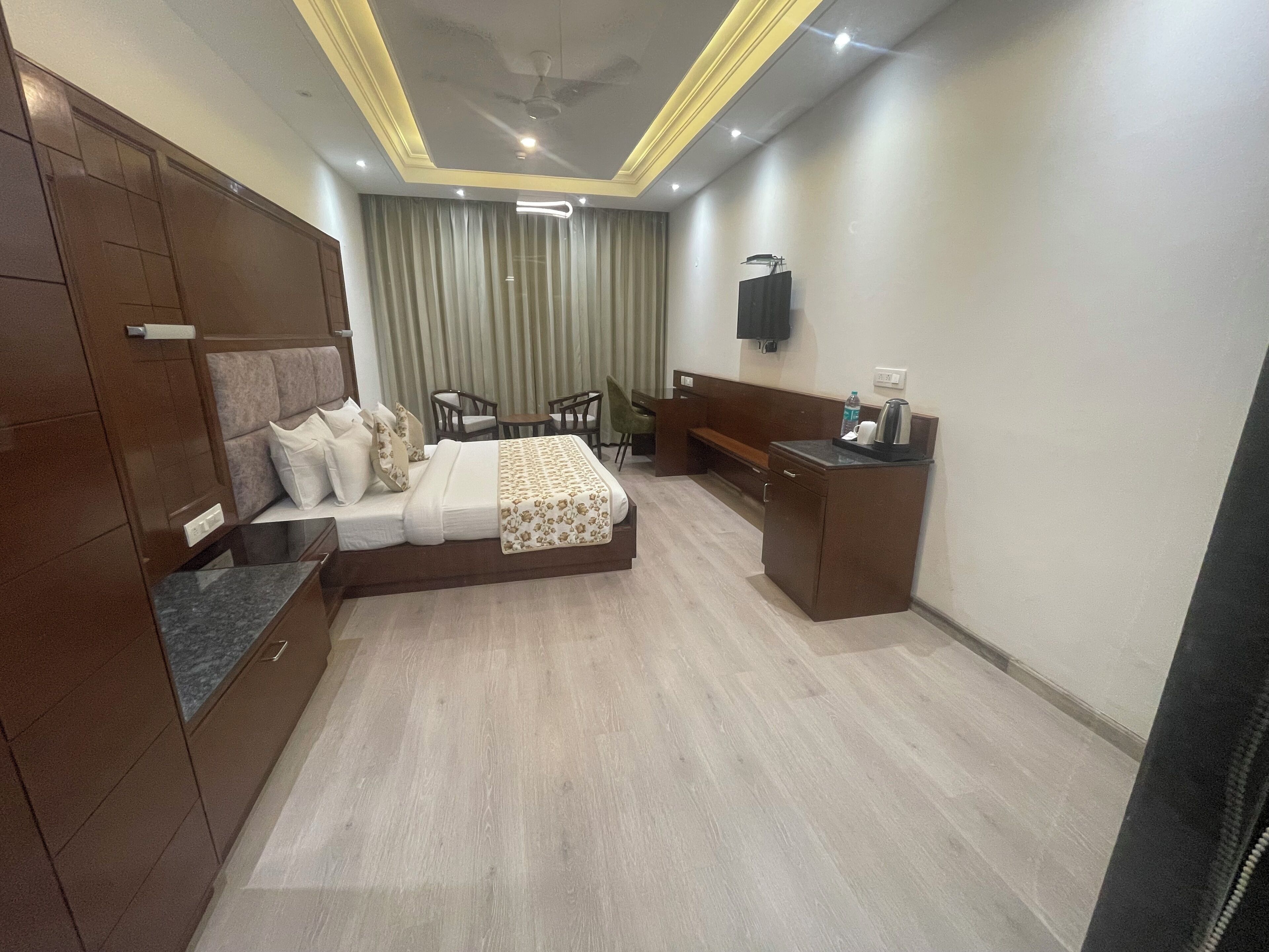 Quarto de hotel com cama, escrivaninha, cadeira, sofá e televisão.