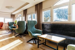 Um interior moderno com um sofá, duas poltronas e uma mesinha.