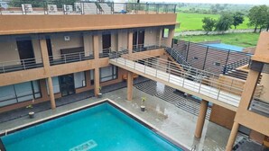 Um edifício com vários andares e piscina no térreo.