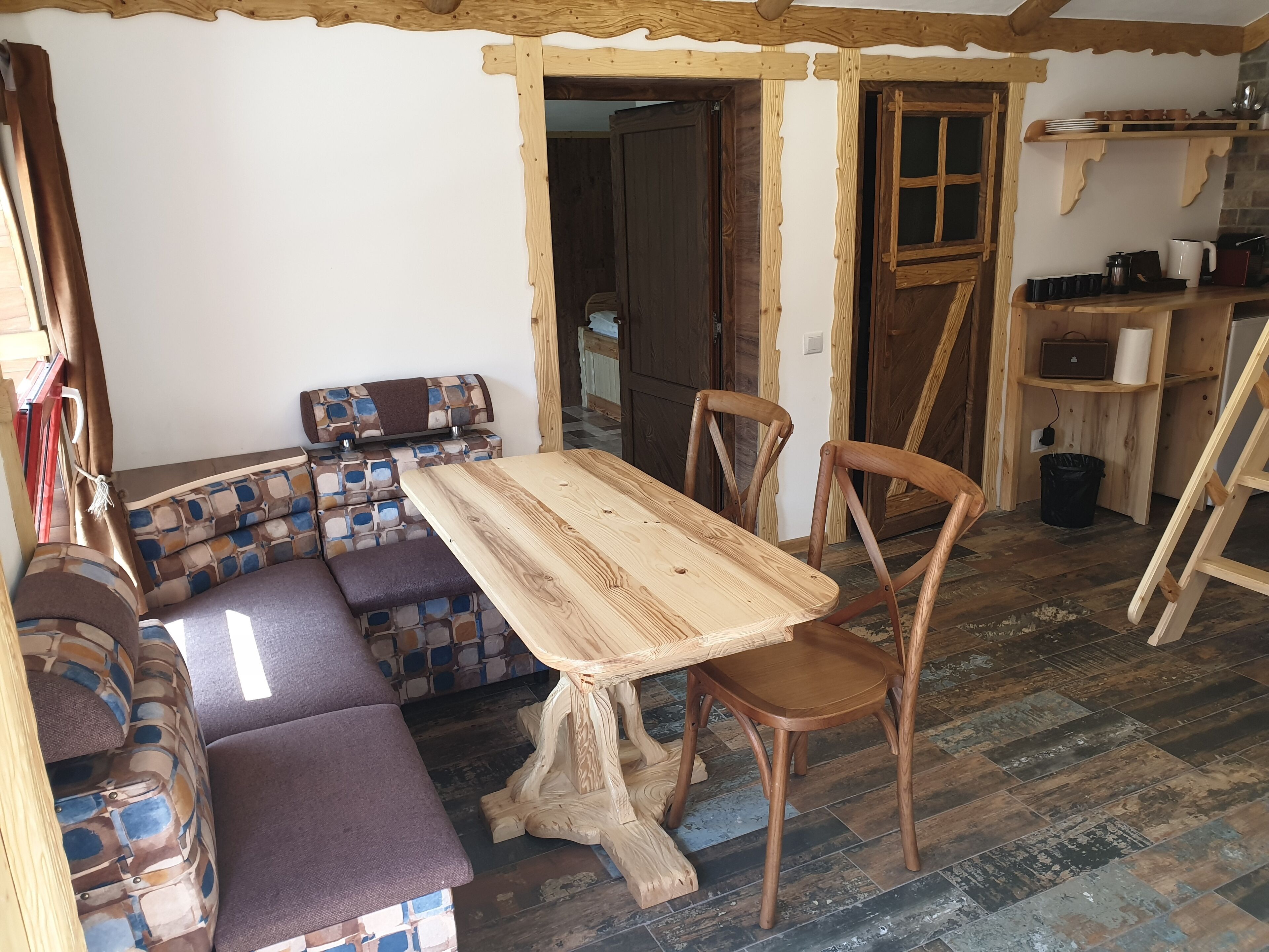 Um quarto acolhedor com uma mesa e cadeiras de madeira, um banco e um sofá estampado.