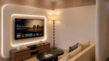 Uma sala de estar moderna com televisão de tela plana, um sofá, uma mesa de centro e um abajur.