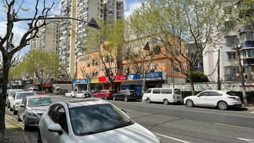 Rua com carros estacionados, edifícios e árvores.