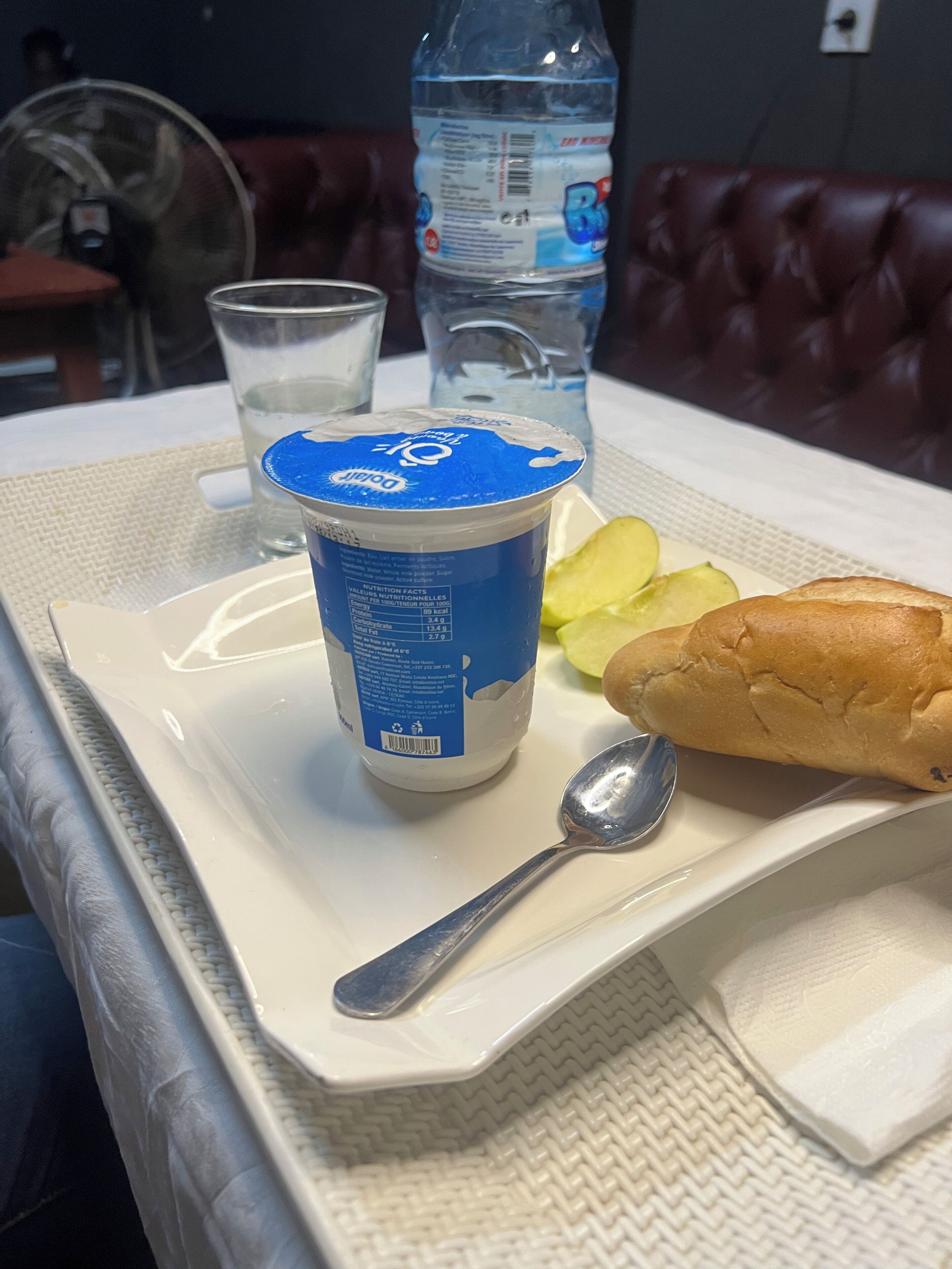 Uma mesa de jantar com um prato de comida, uma garrafa de água, um copo e uma colher.