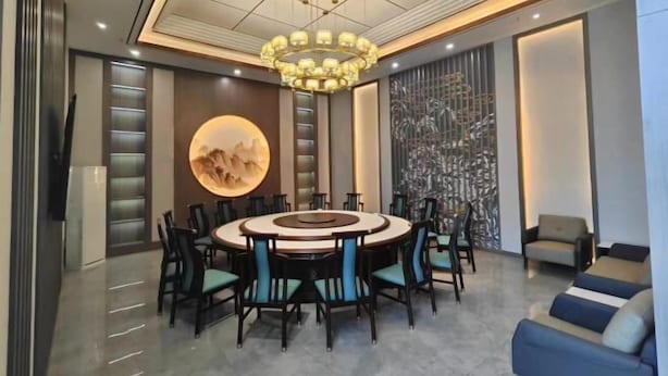 Uma área de refeições moderna com uma mesa redonda e cadeiras, um lustre e um painel decorativo.