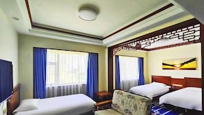 Quarto de hotel com duas camas, um sofá, uma televisão e um painel decorativo na parede.