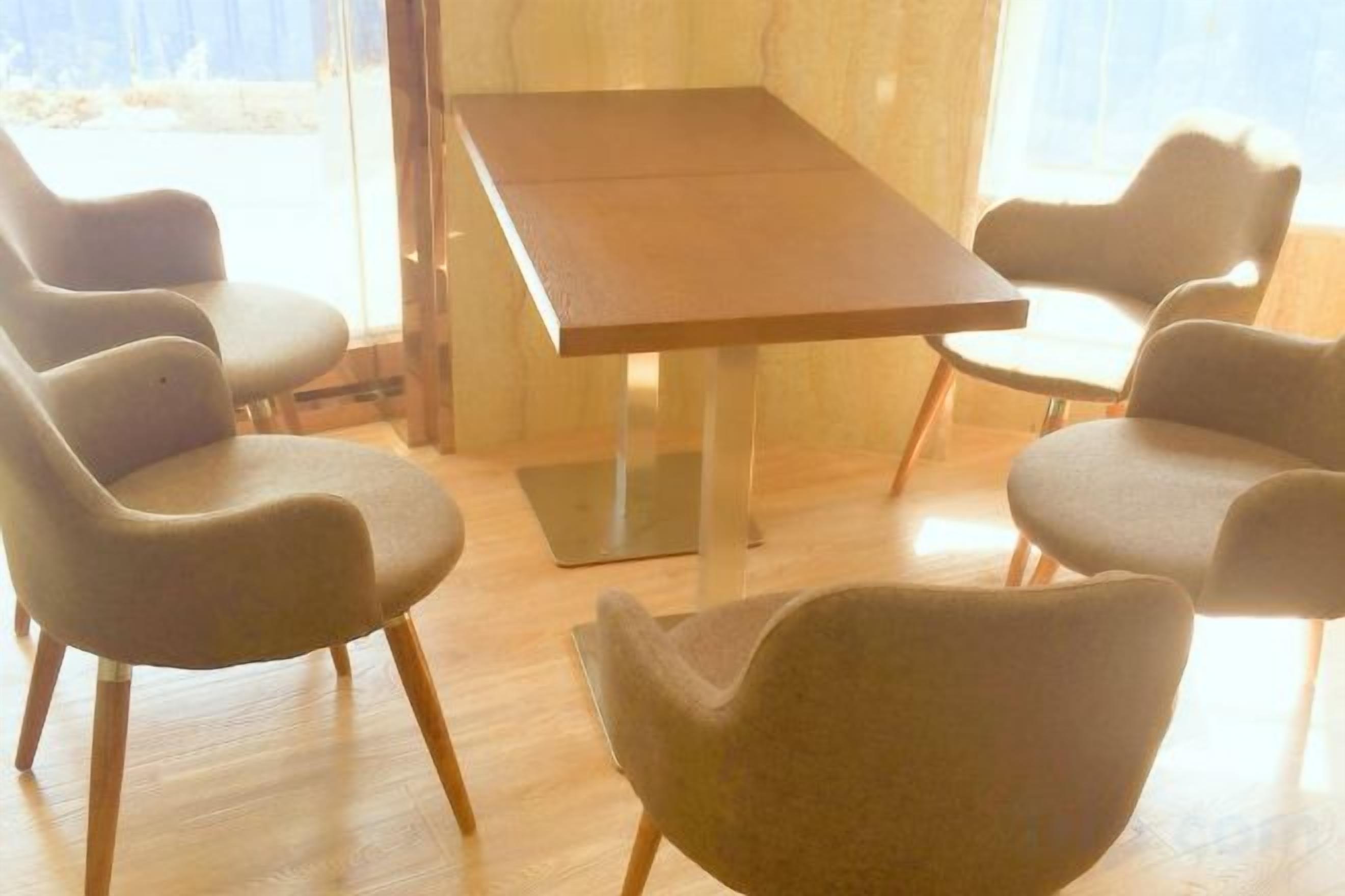 Quarto com uma mesa de madeira cercada por quatro cadeiras, um separador de vidro e vista pela janela.