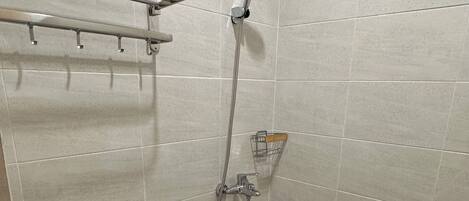 Um banheiro pequeno e moderno com vaso sanitário, chuveiro com ducha manual e porta-toalhas.