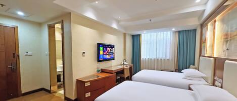 Quarto de hotel com duas camas, uma escrivaninha, uma televisão e uma janela com cortinas.
