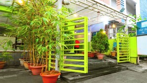 Entrada de um edifício com portão verde, plantas em vasos e uma placa com a inscrição 'blue da'.