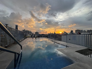Uma piscina no terraço com um horizonte urbano ao fundo.