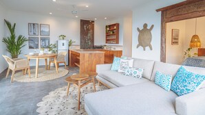 Uma sala de estar moderna com sofá, mesa de centro e cadeiras, uma área de cozinha e uma mesa de jantar.