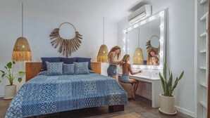 Quarto com cama, penteadeira com espelho e duas luminárias pendentes.