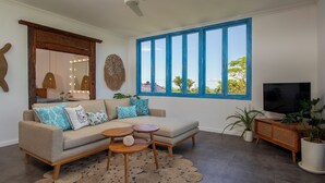 Uma sala de estar com sofá, mesa de centro redonda e televisão.