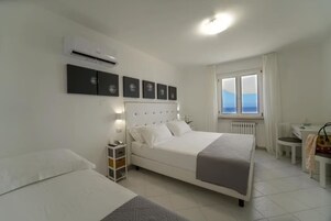 Quarto com cama, mesa de cabeceira e janela com vista.