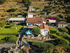 Vista aérea de uma propriedade residencial com vários edifícios, um jardim bem cuidado e uma piscina.