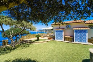 Um imóvel costeiro com fachada em azulejos, parede de pedra e vista para o mar.