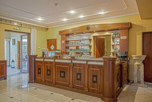 Uma área de bar com armários de madeira, prateleiras com copos e um pedestal de mármore.