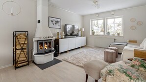 Uma sala de estar moderna com lareira, móveis brancos e uma janela ampla que proporciona iluminação natural.