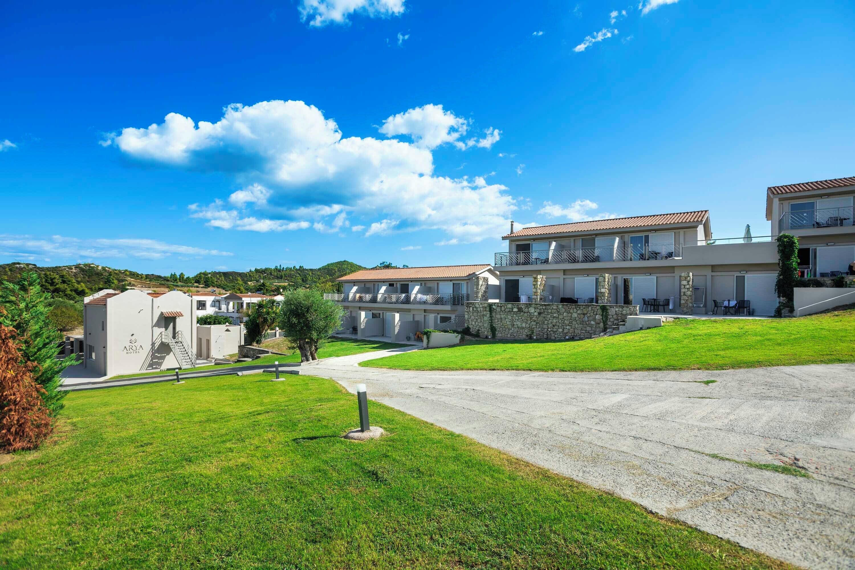 Um bairro residencial com calçada pavimentada, gramado e um prédio de vários andares com varandas.