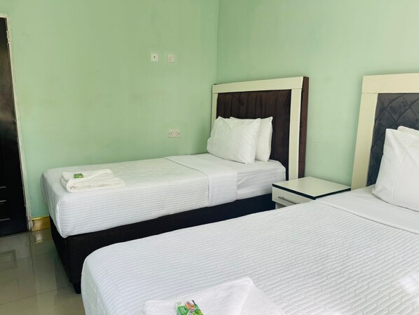Quarto de hotel com duas camas de solteiro, uma mesa de cabeceira e um armário.